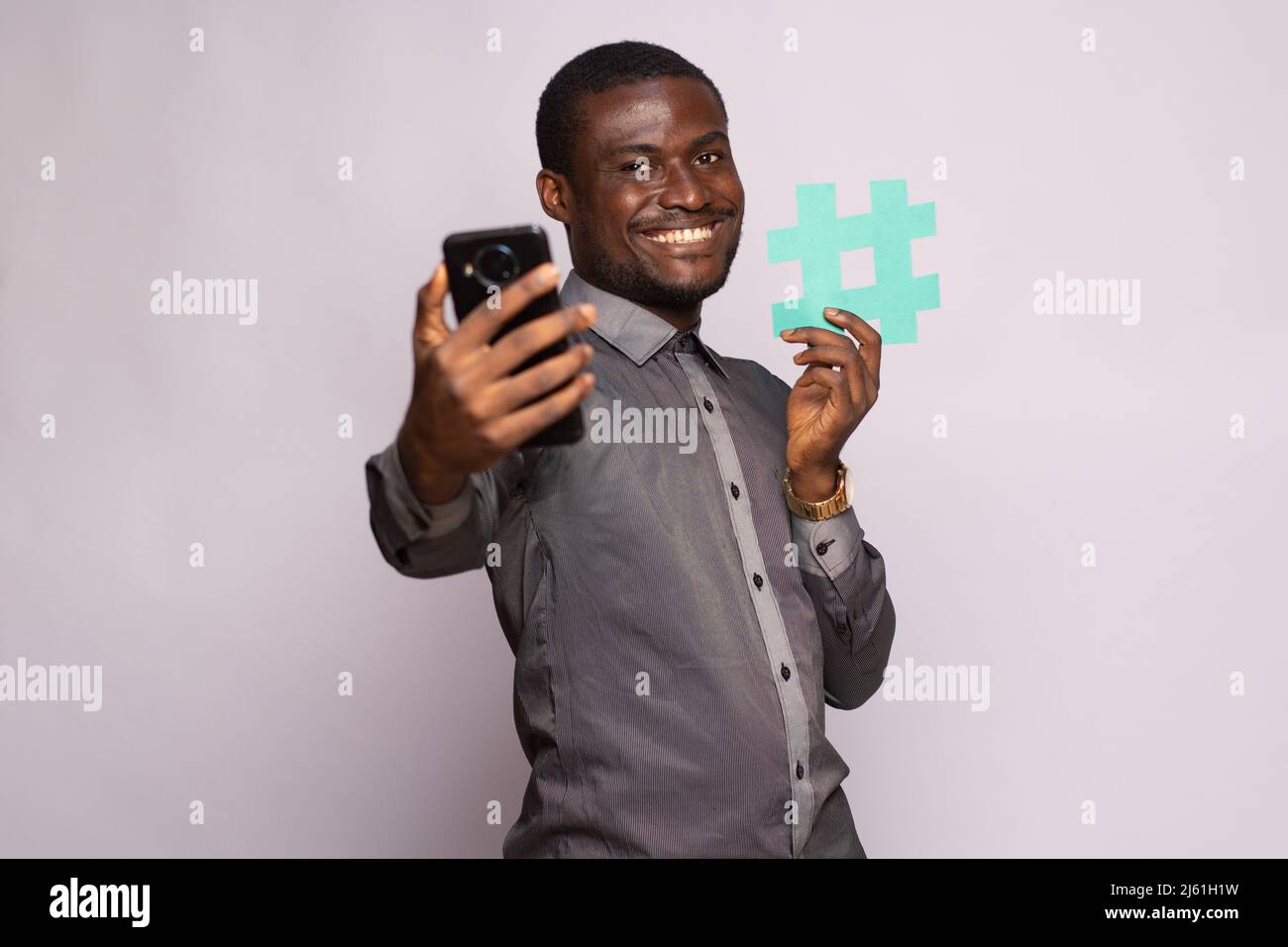 excited black man holding phone and hash tag symbol Stock Photo - Alamy