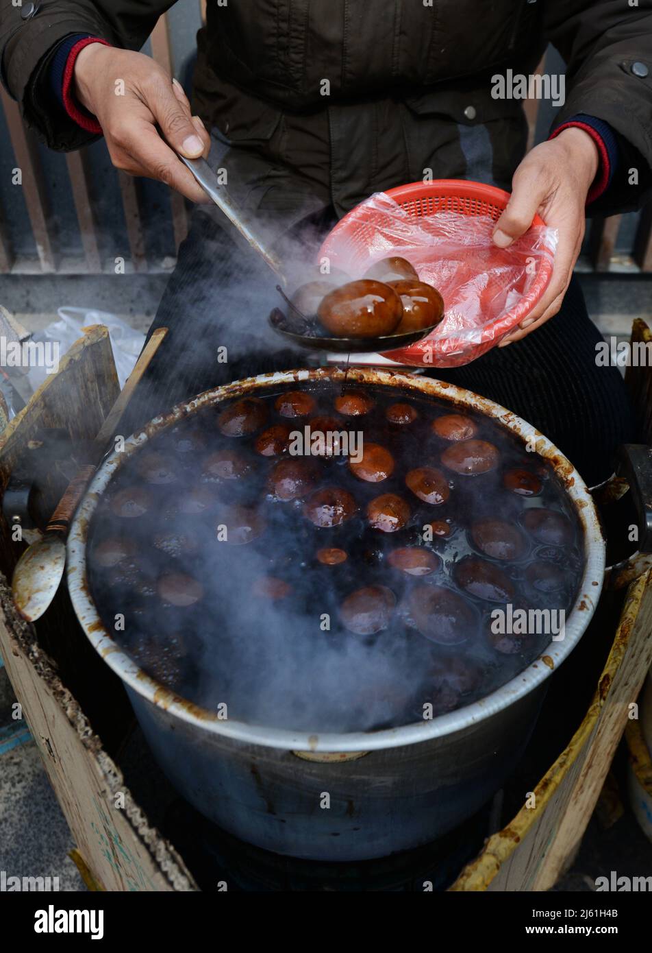 A local woman cooking traditional Tea leaf eggs. The eggs are cooked in ...