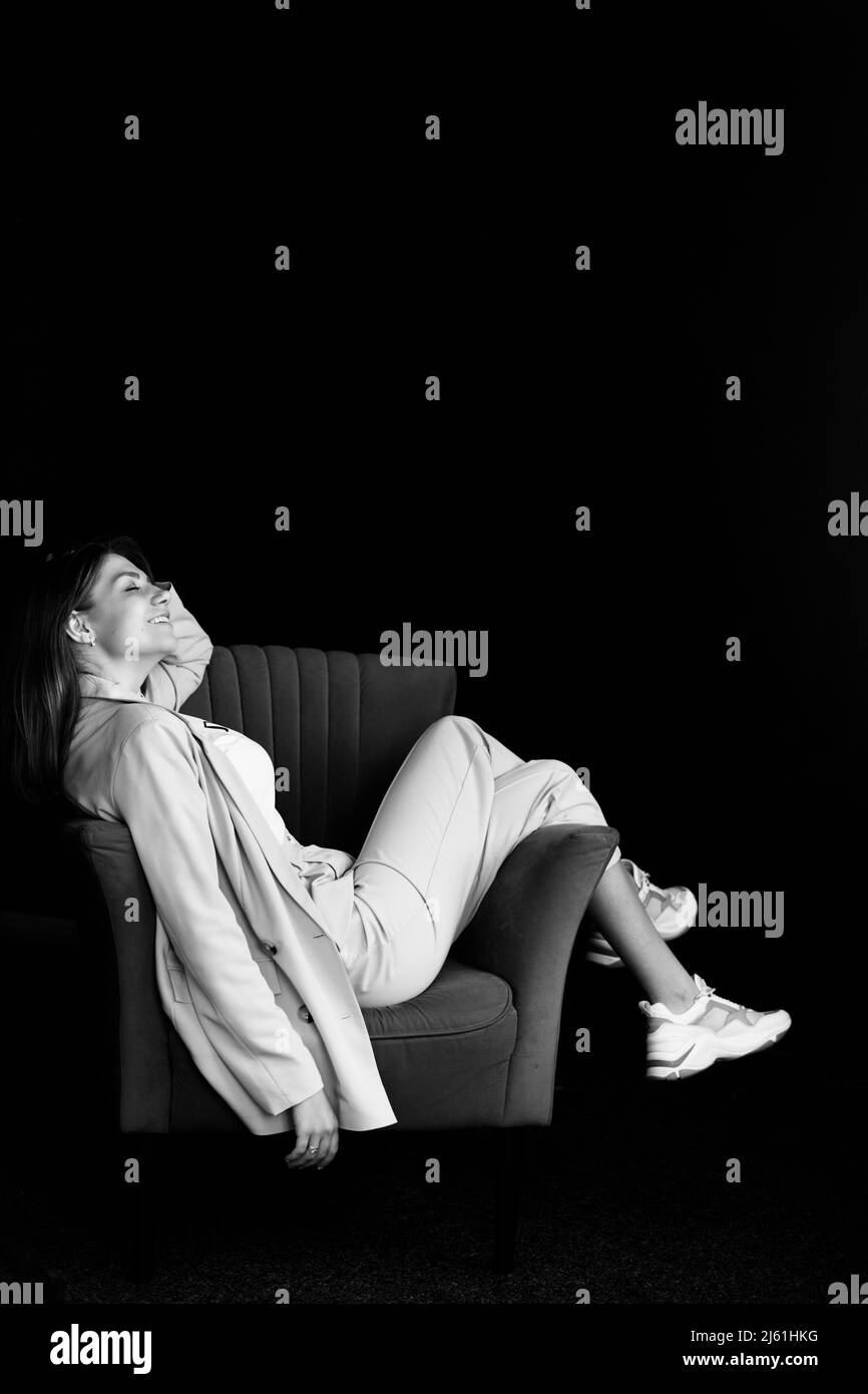 Portrait of stylish beautiful woman sitting on chair in studio ...
