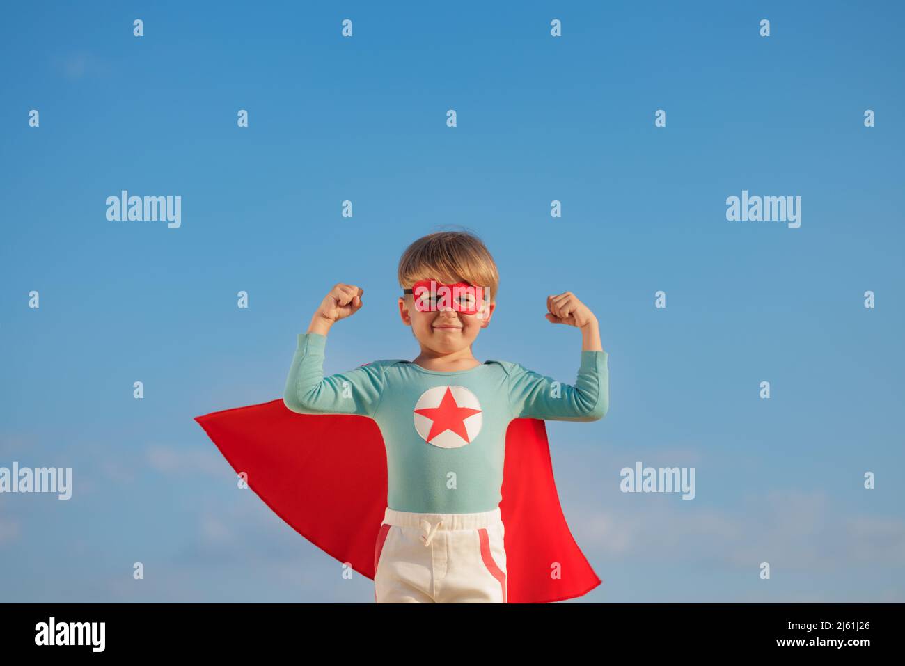 Superhero child playing outdoor. Super hero kid against blue summer sky ...
