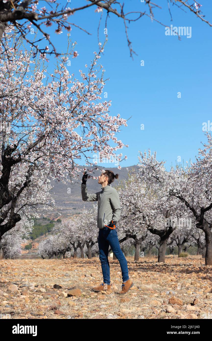 Young man gardener smelling flowers sorrounded by rural landscape under ...