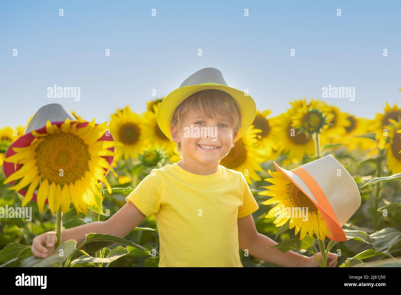 Happy child having fun in spring field of sunflowers. Outdoor portrait ...