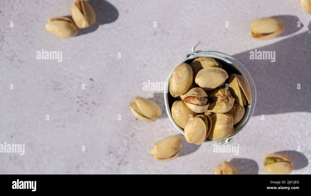 Pistachios in white bucket on concrete background. Healthy and dietary ...