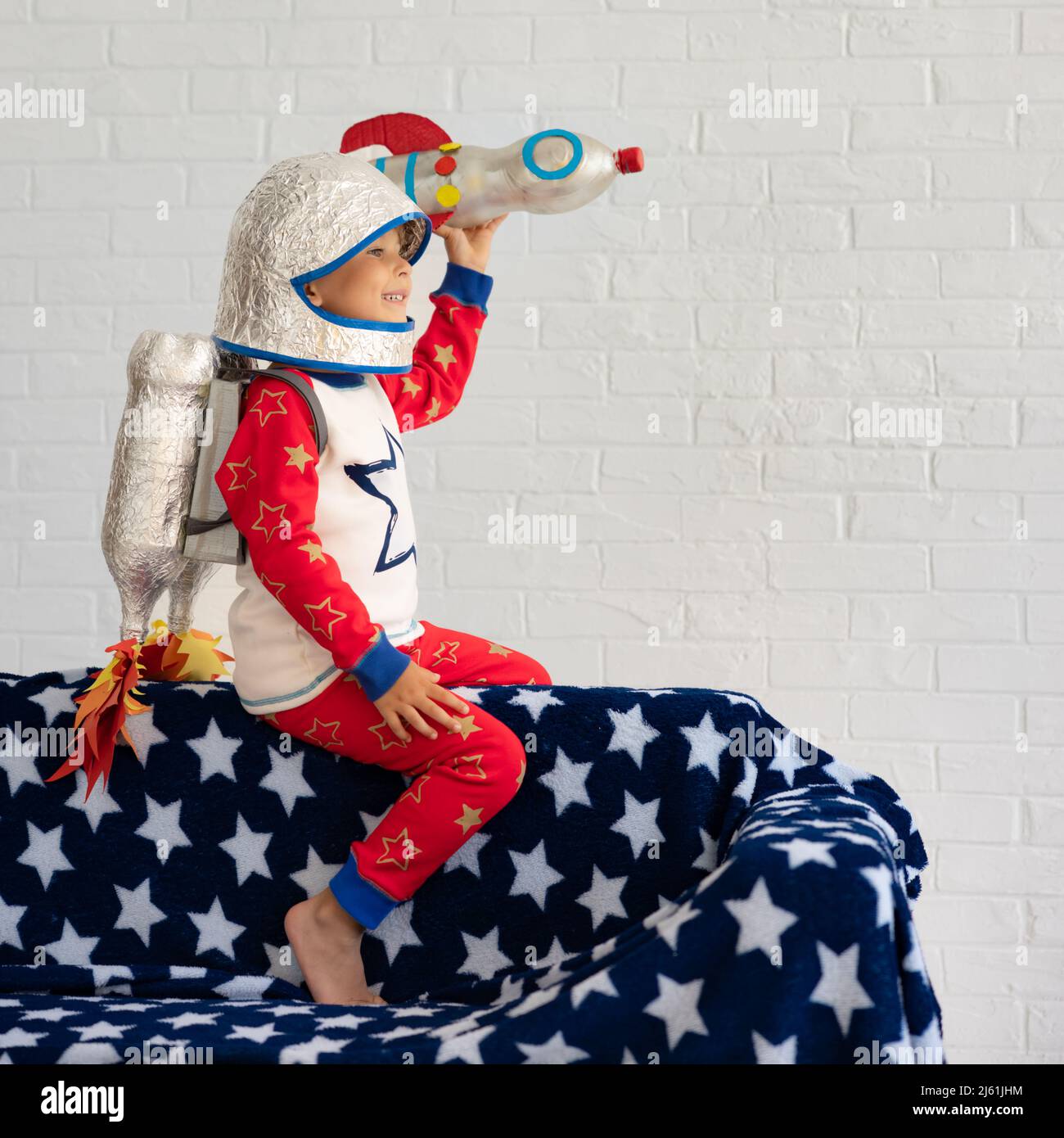 Happy kid with craft toy rocket. Child playing at home against white ...