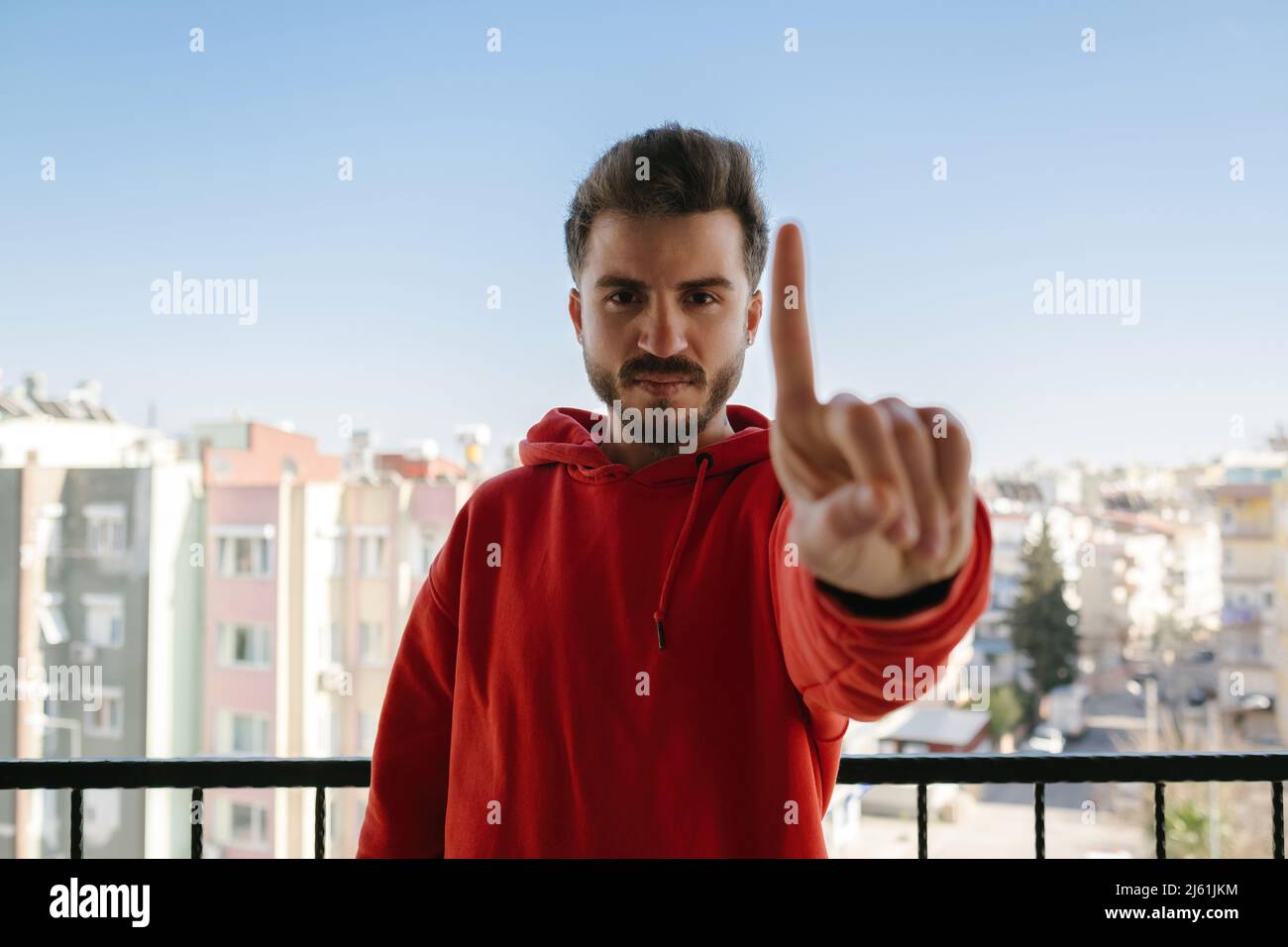 Hand sign, the young man on the balcony makes a sign with his fingers ...
