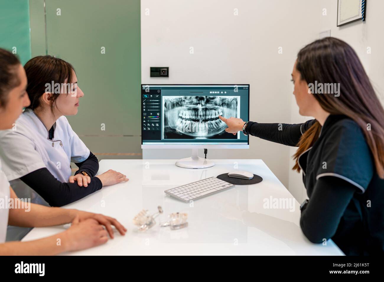Dentist discussing with nurses over x-ray in computer at office Stock ...