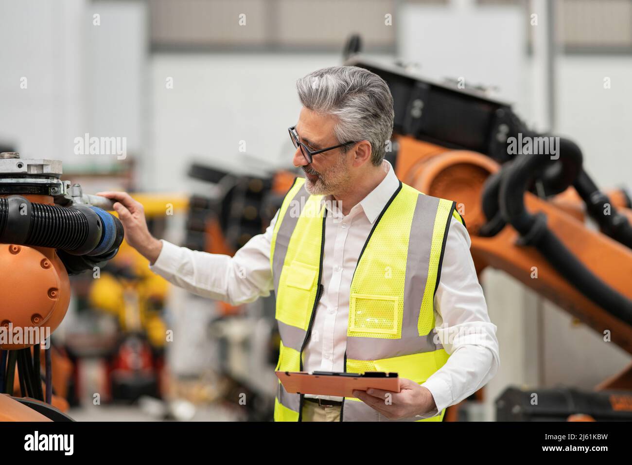 Technician holding file folder checking robotic arm in warehouse Stock ...