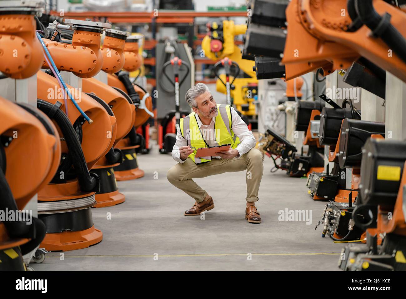 Technician holding file folder analyzing robotic arm in factory Stock ...