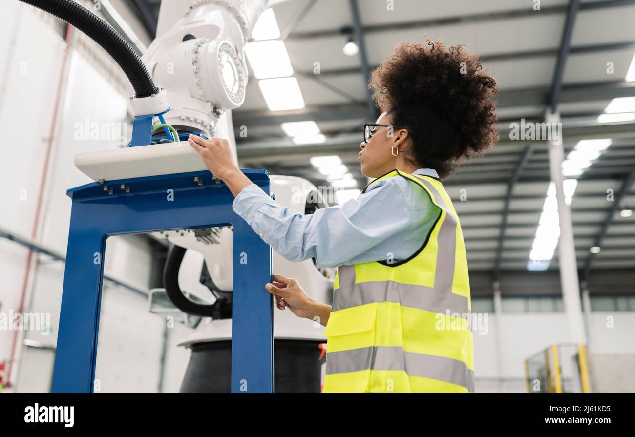 Technician examining robotic arm machine in factory Stock Photo - Alamy