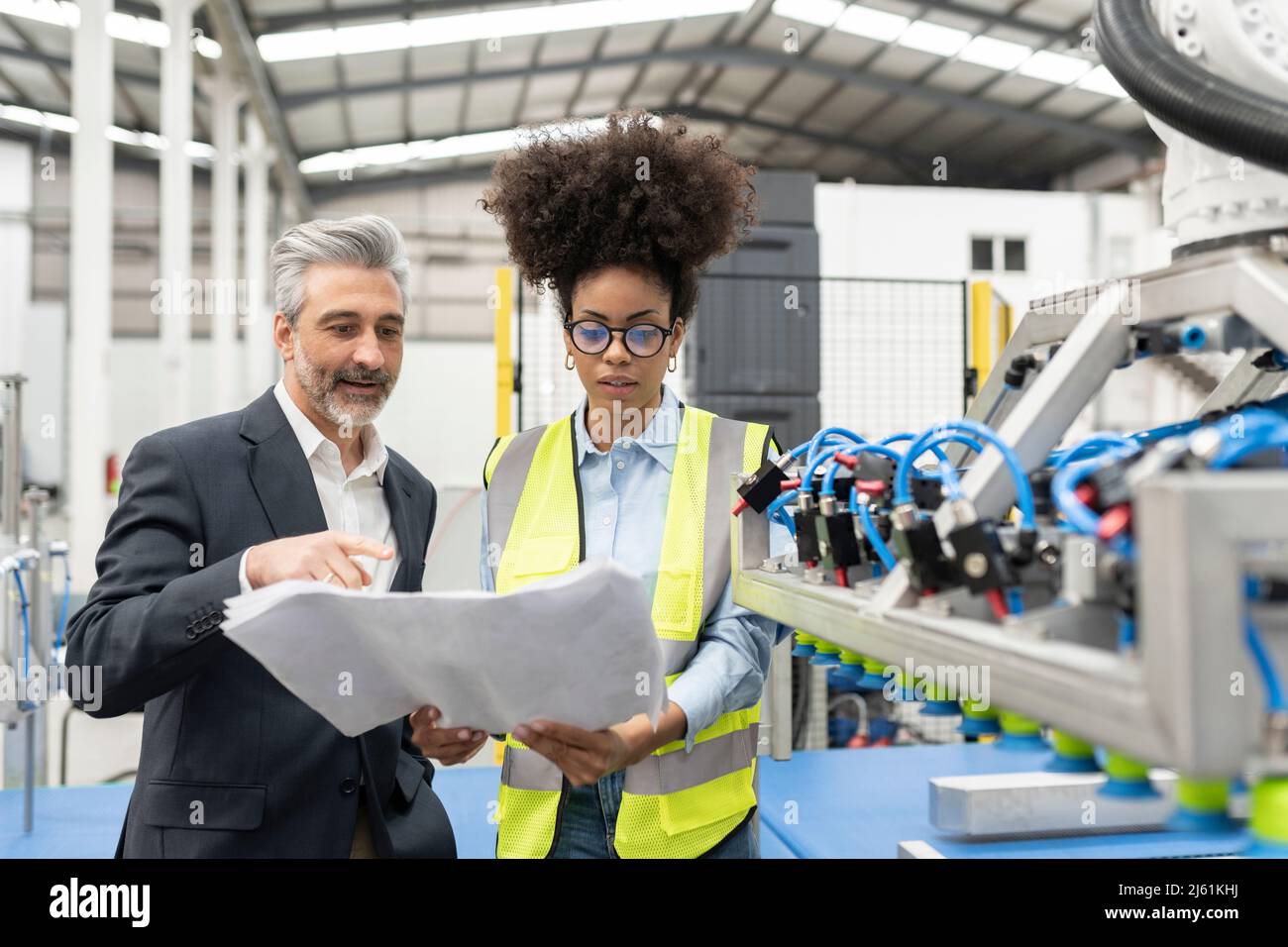 Businessman discussing over blueprint with engineer in factory Stock ...