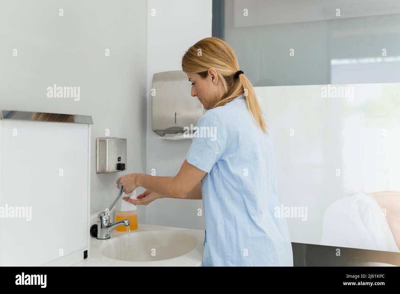 Dentist in uniform washing hands at dental clinic Stock Photo - Alamy