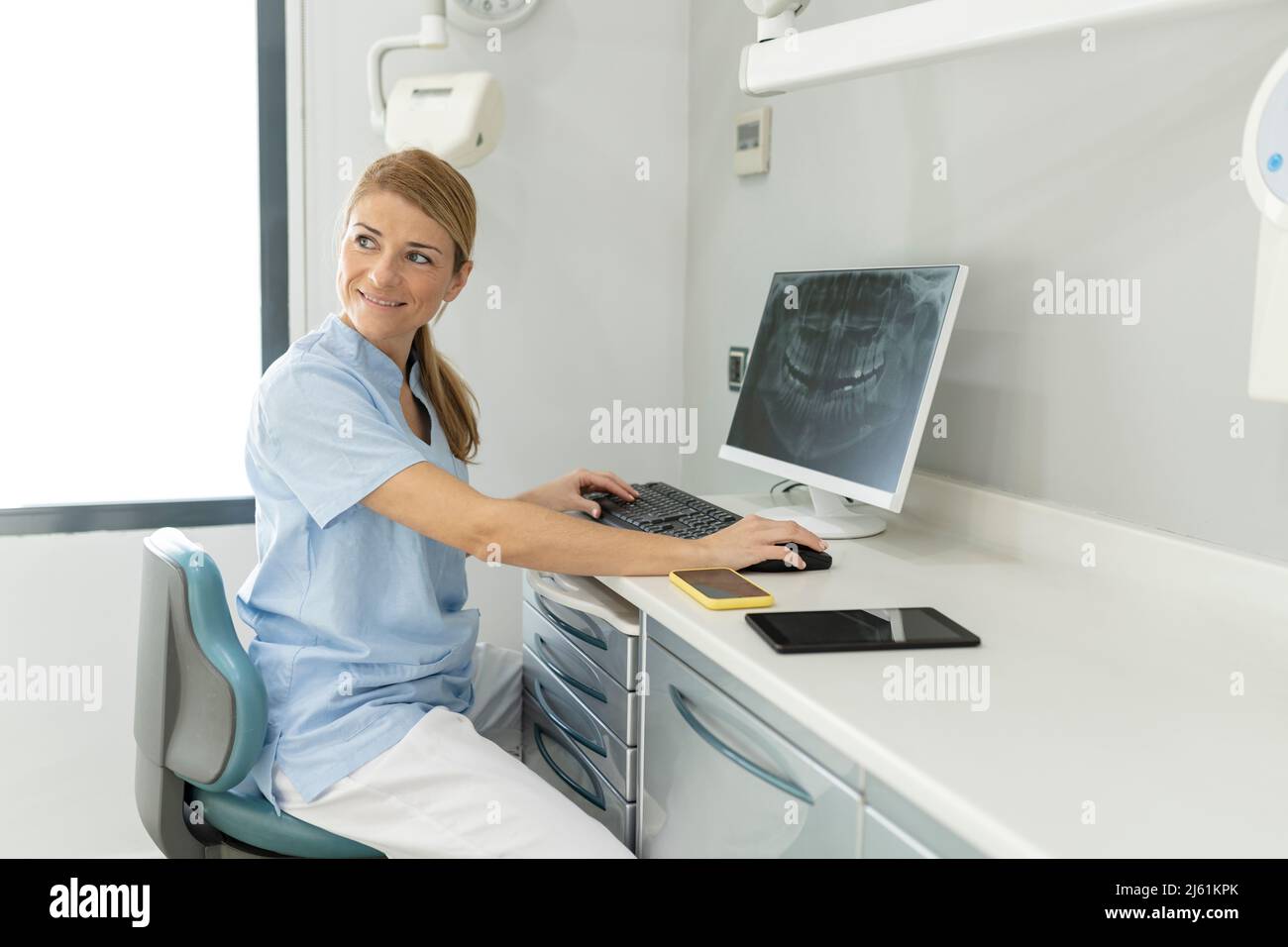 Dentist sitting on chair with computer on desk at dental clinic Stock ...