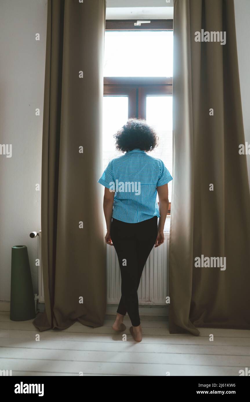 Woman looking out through window at home Stock Photo - Alamy