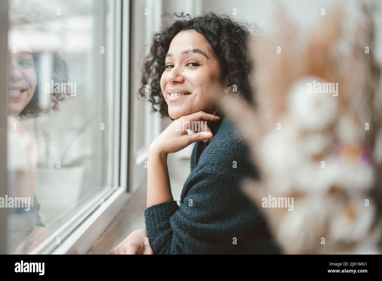 Happy beautiful woman standing by window at home Stock Photo - Alamy