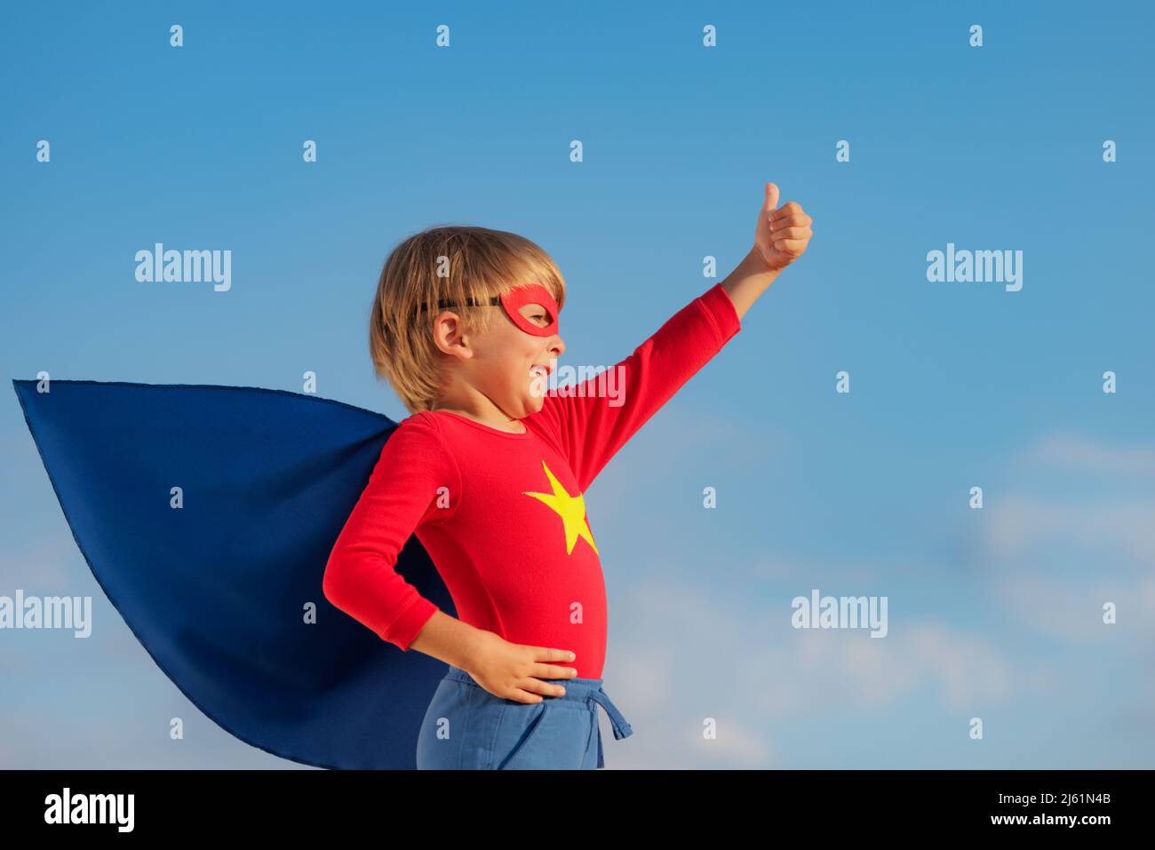 Superhero child playing outdoor. Super hero kid against blue summer sky ...
