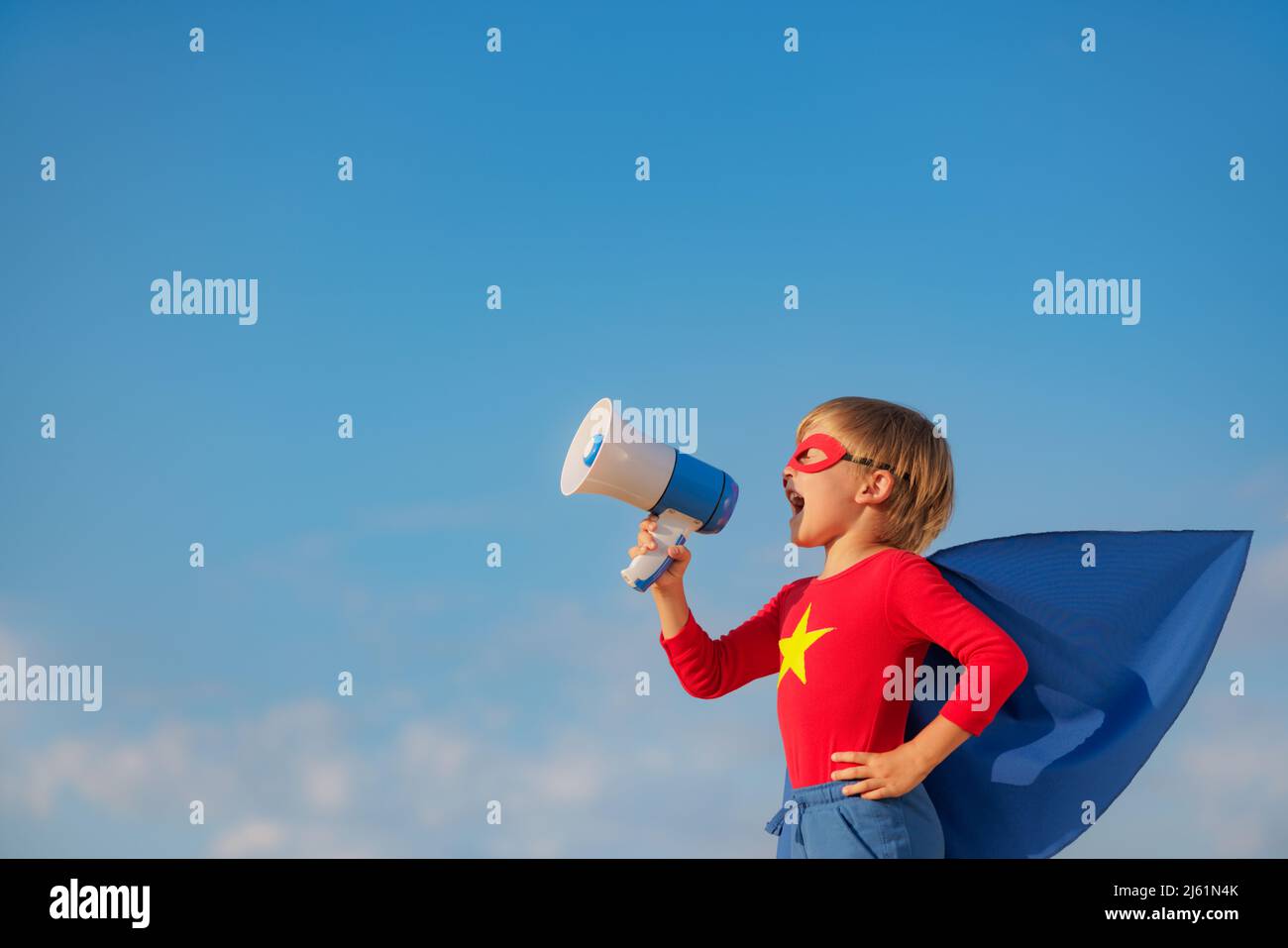 Superhero child shouting through loudspeaker outdoor. Super hero kid ...