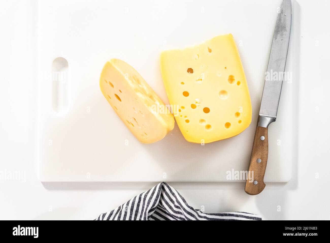 Large slice of semi soft part skim cheese on a white cutting board ...