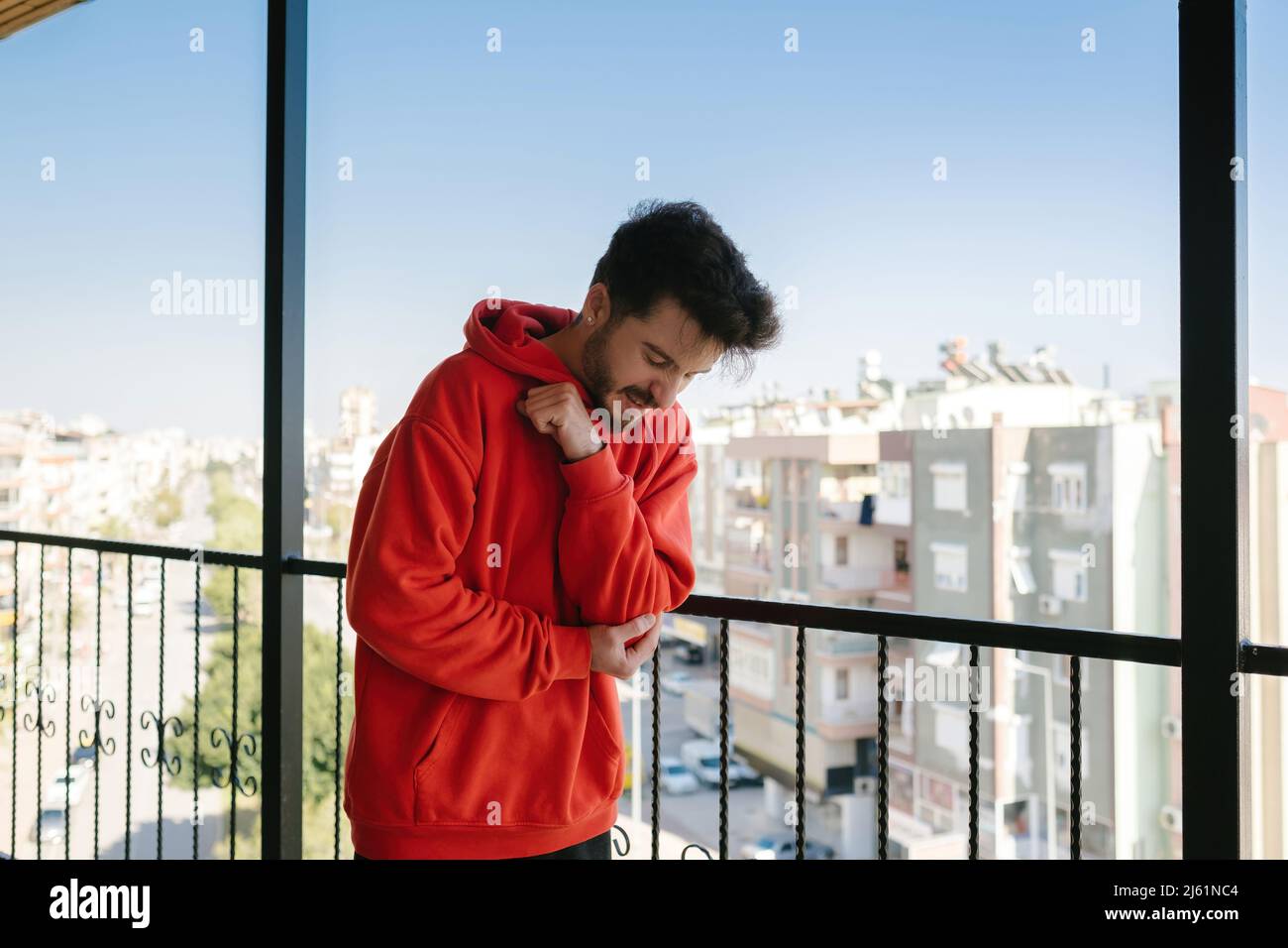 Elbow pain, the young man has hit his elbow on the balcony rails and is ...