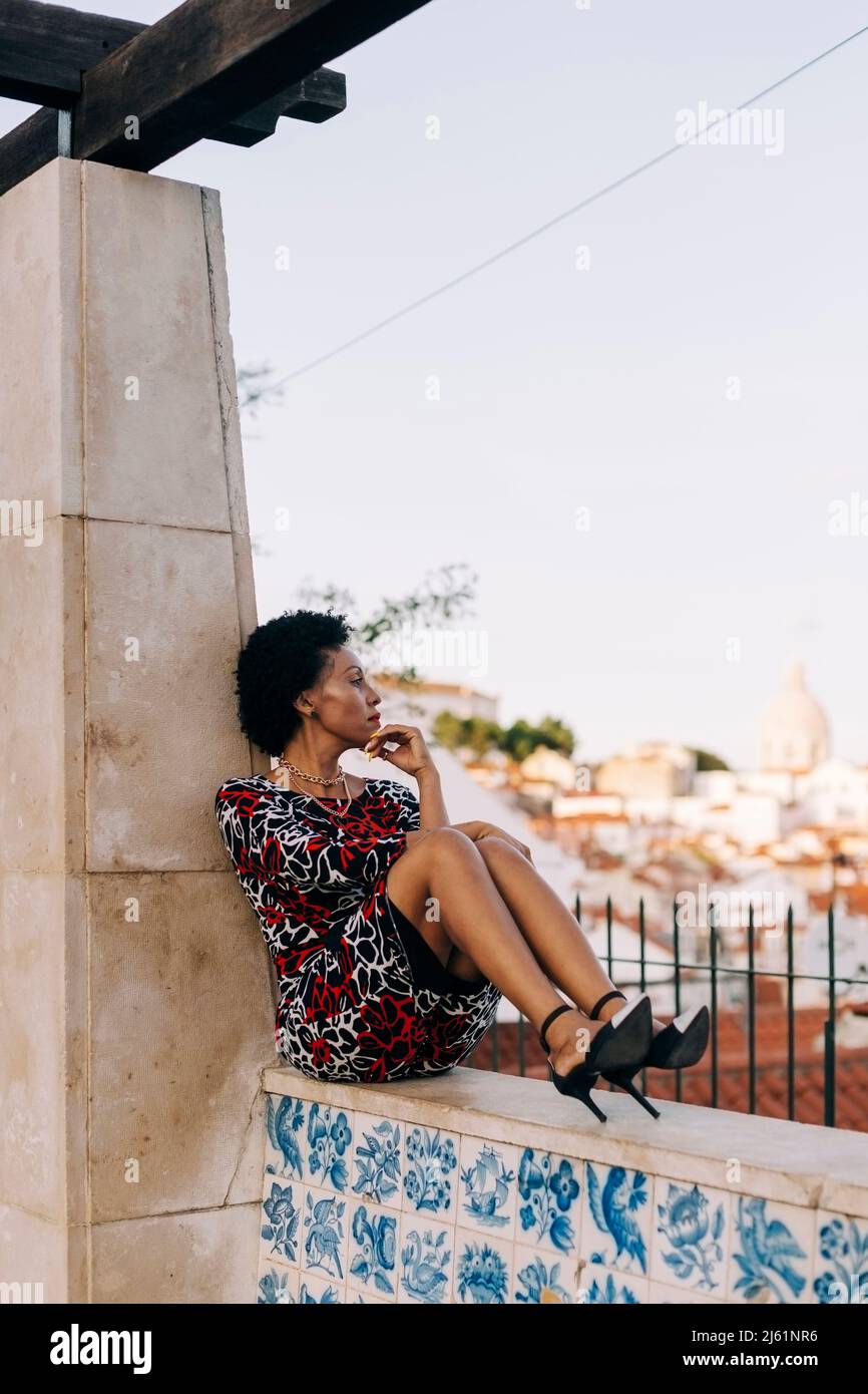 Contemplative woman sitting on wall Stock Photo - Alamy