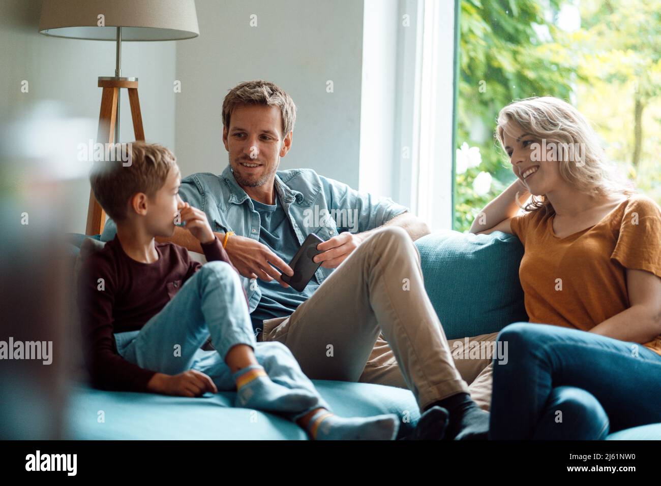 Son talking with mother and father sitting on sofa in living room Stock ...