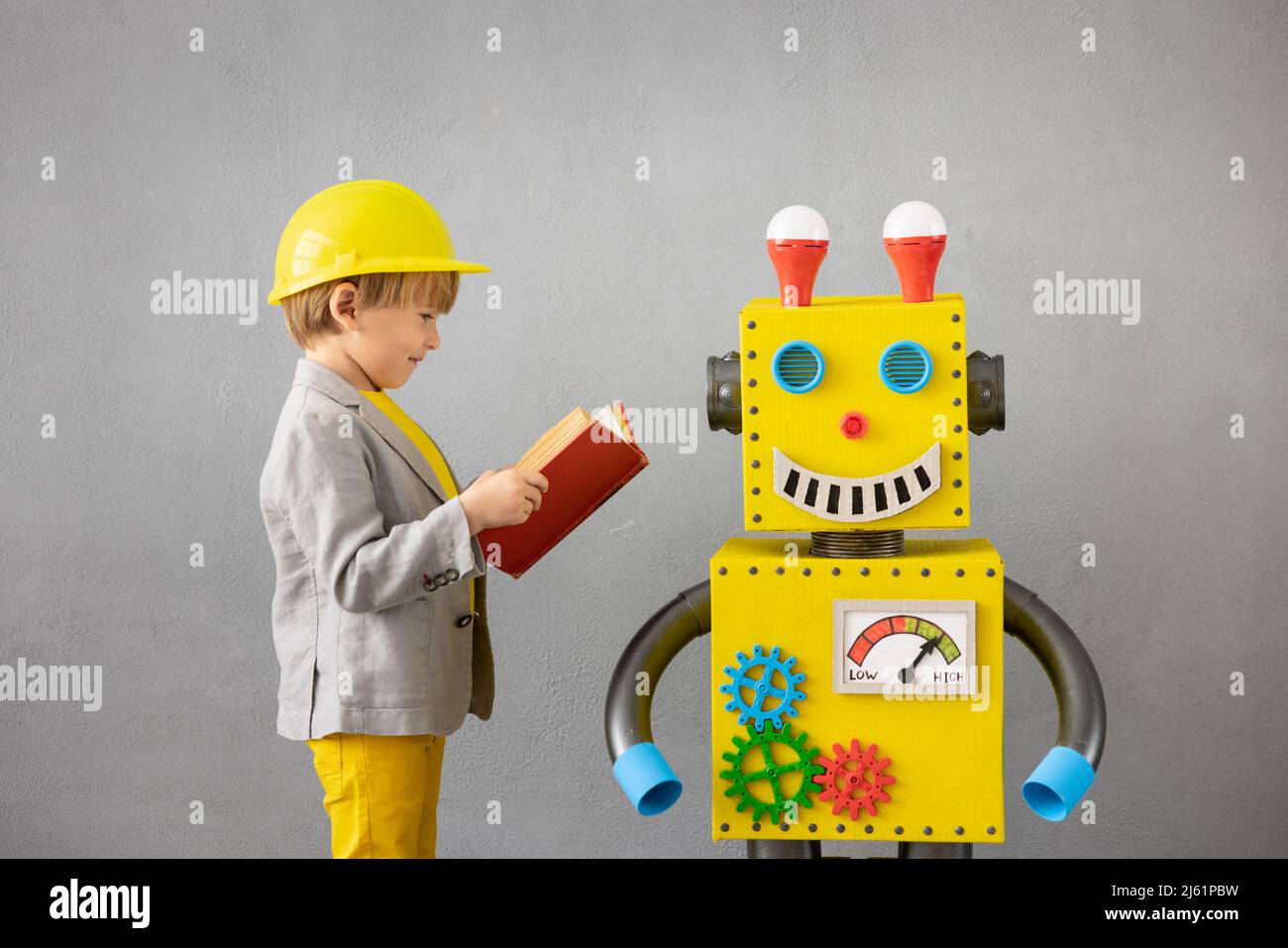 Happy child with robot. Funny kid playing at home. Boy reading book ...