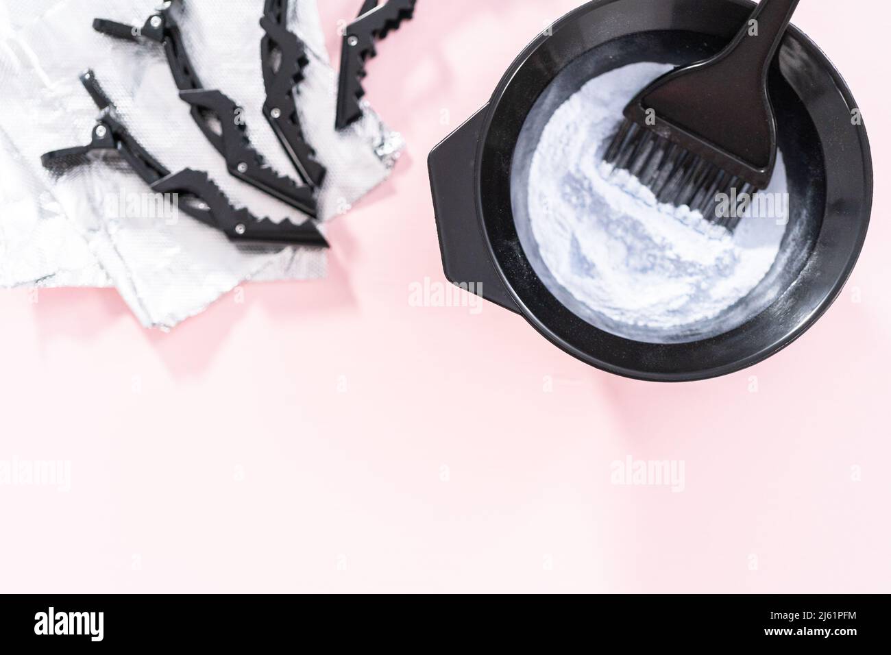Hair color dye powder in a black plastic mixing bowl on a pink ...