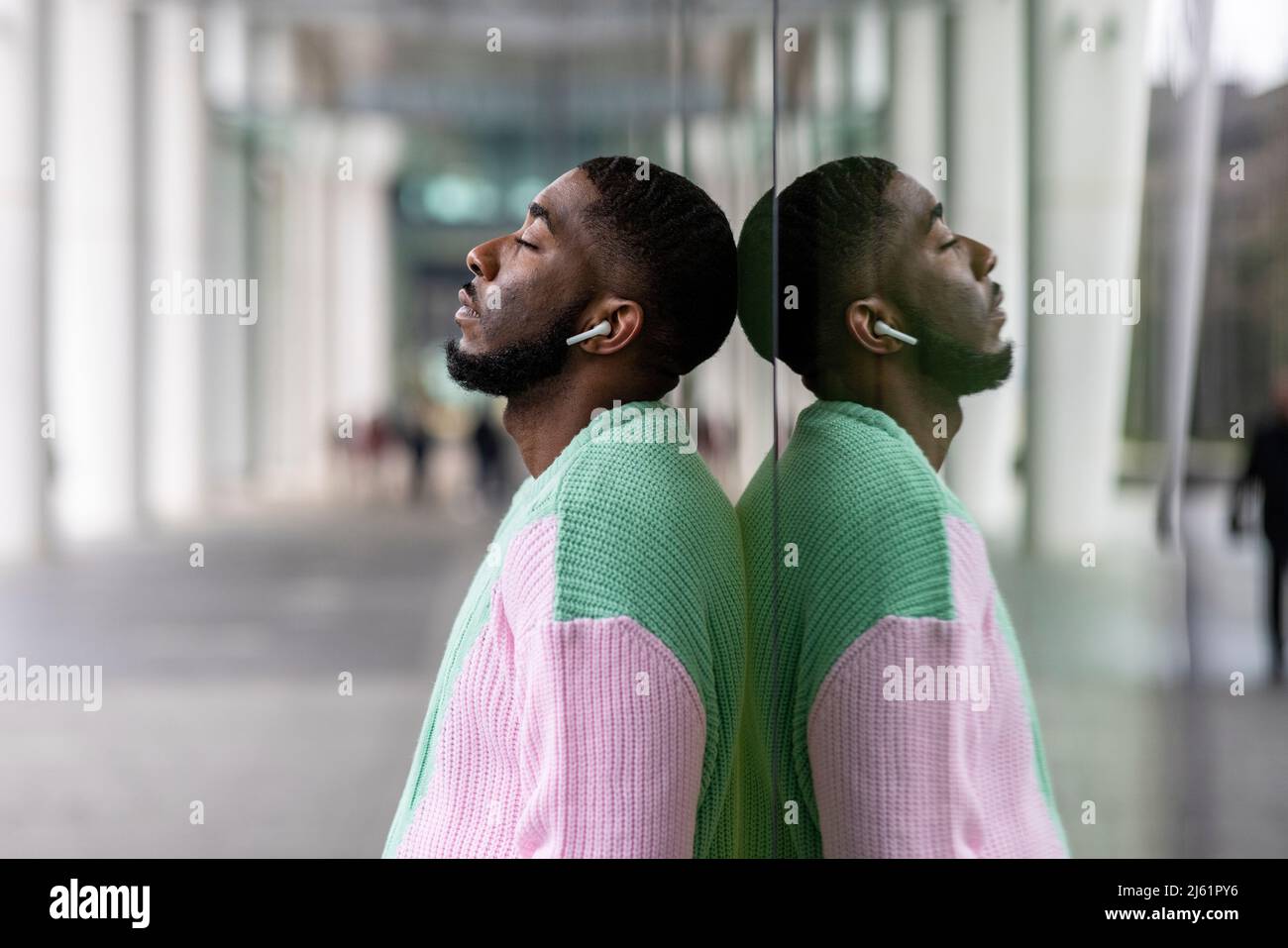 Man with eyes closed listening music through wireless in-ear headphones ...