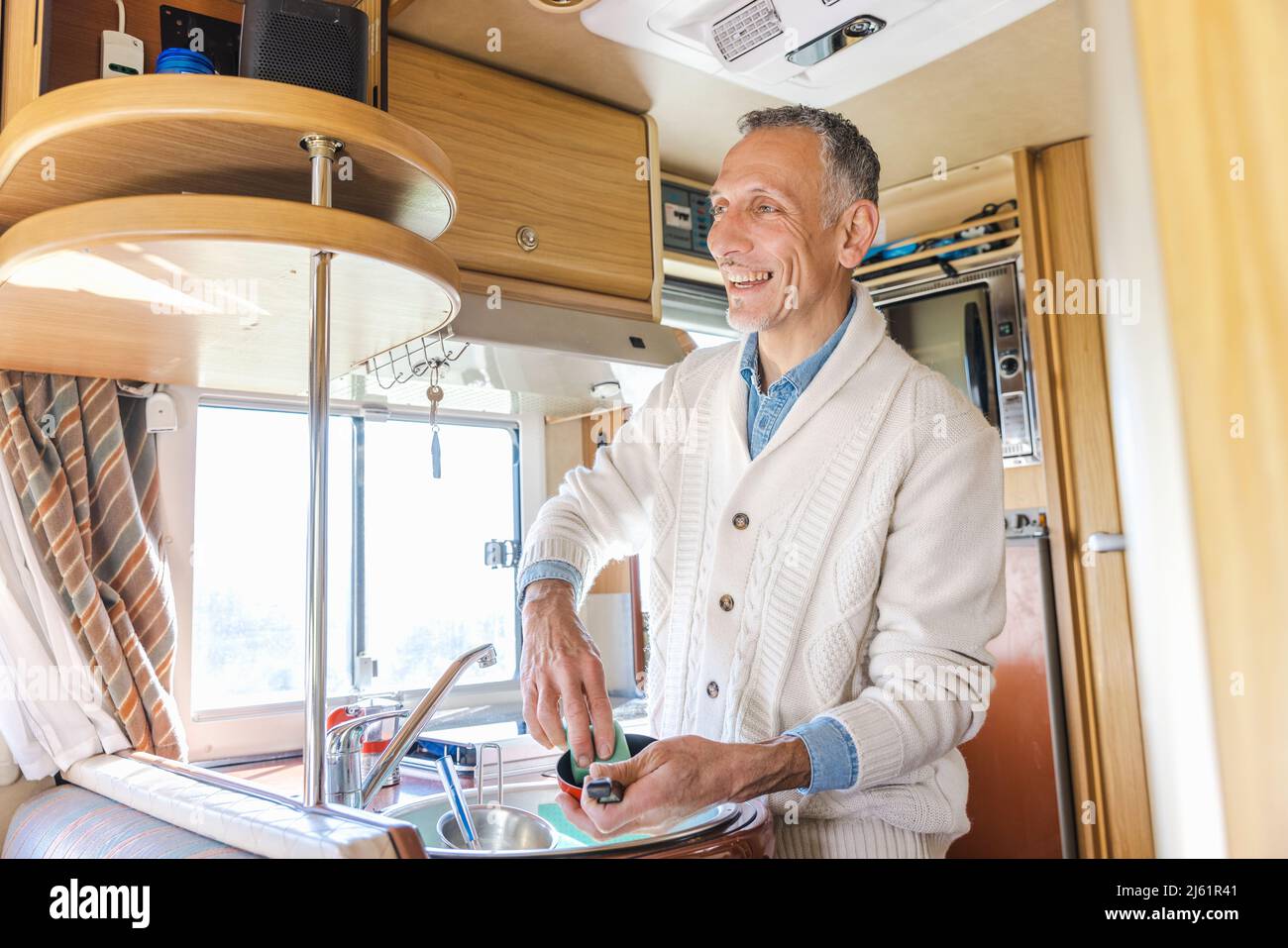 Smiling man washing up in motor home Stock Photo - Alamy