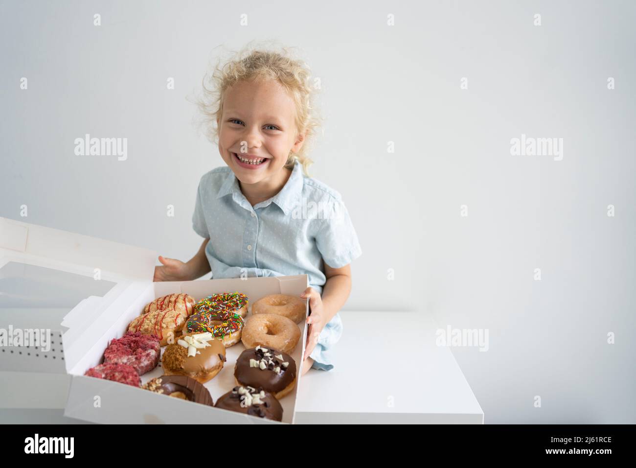 Smiling girl holding box of doughnuts Stock Photo - Alamy