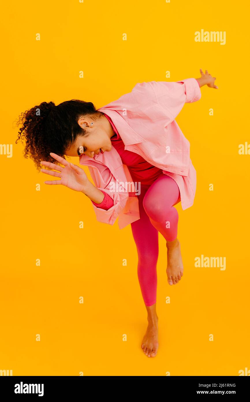 Young woman with eyes closed dancing against yellow background Stock ...