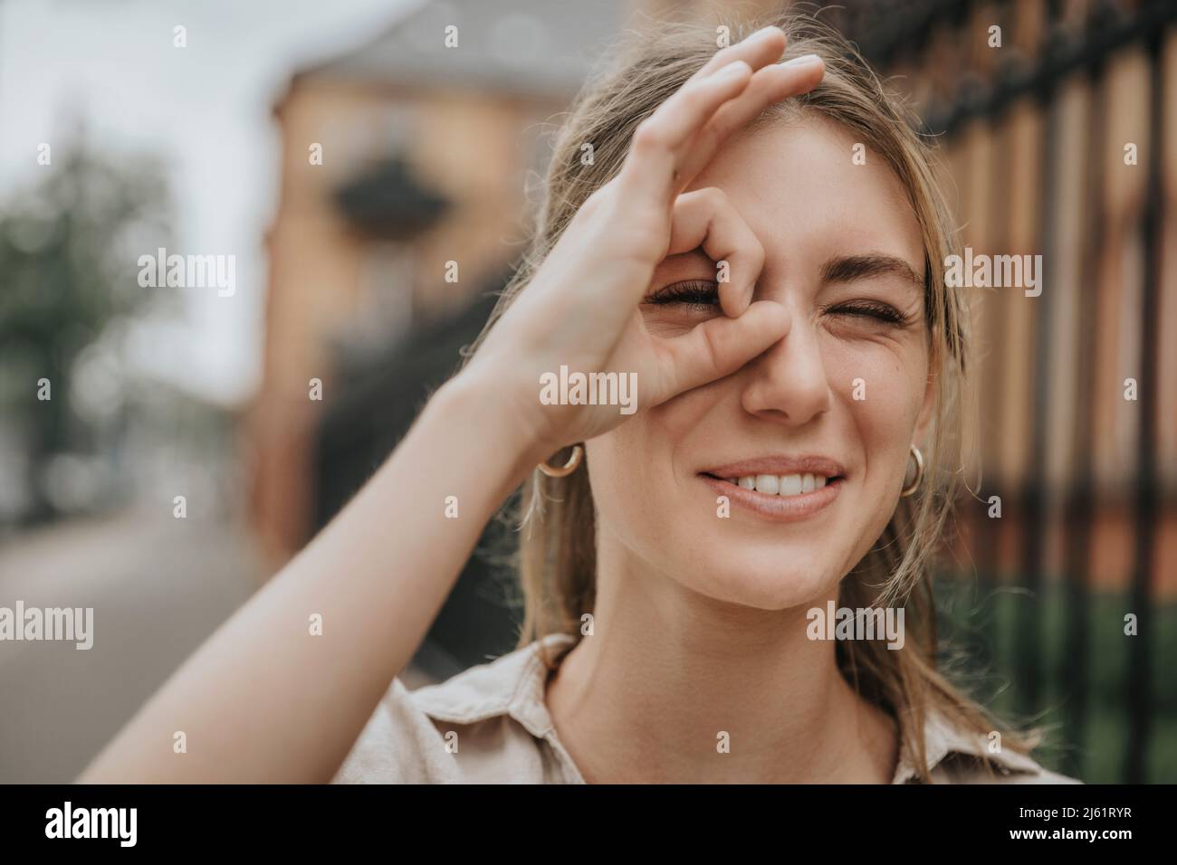 Smiling young woman winking eye gesturing OK sign Stock Photo - Alamy