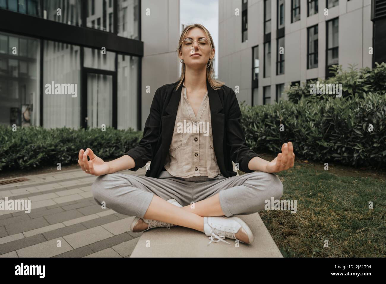 Young woman with eyes closed practicing lotus pose on ledge Stock Photo ...
