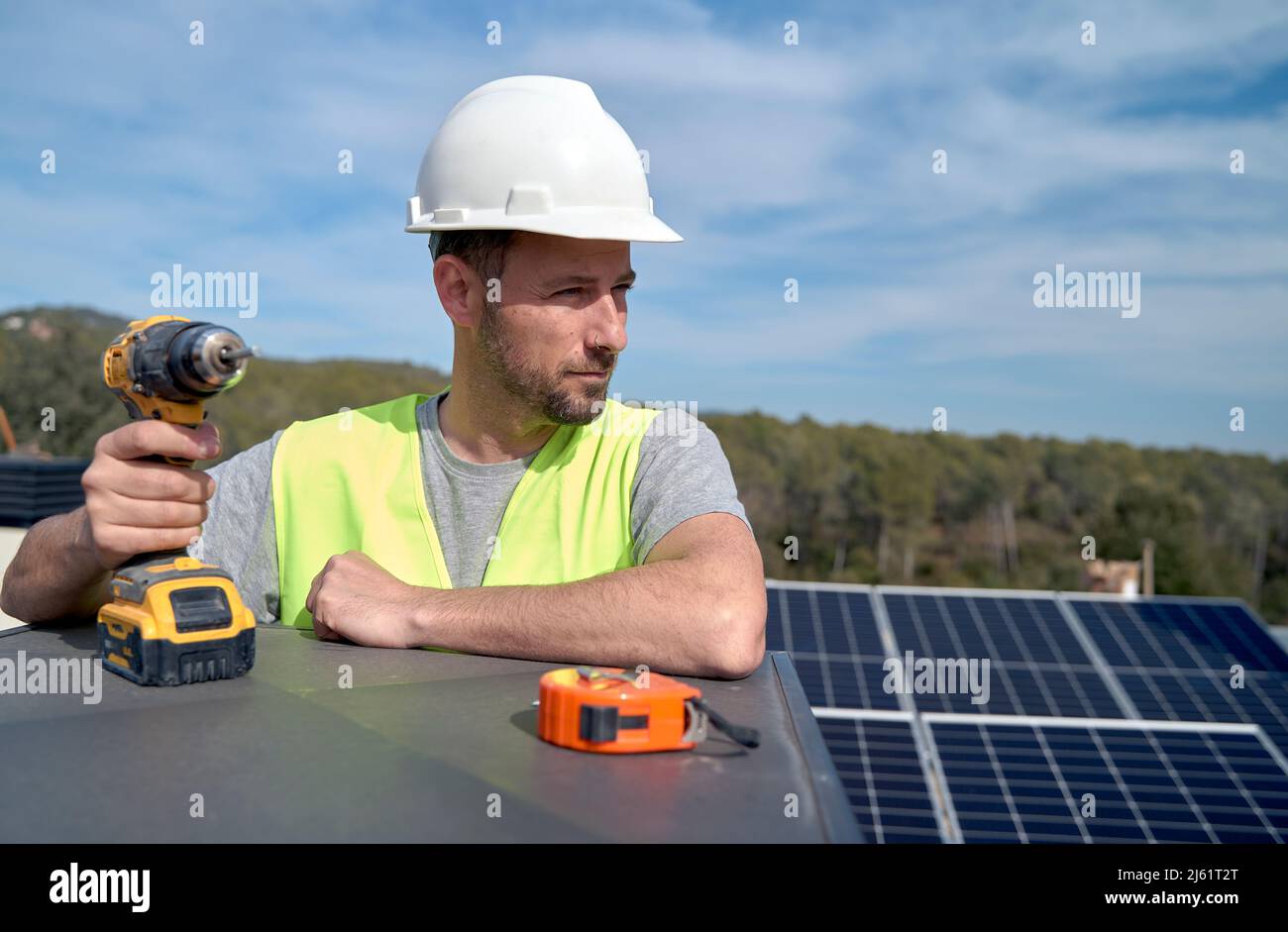 Engineer with drill installing solar panels on sunny day Stock Photo ...