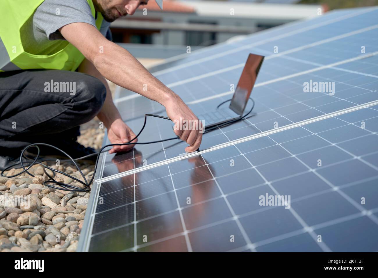 Engineer plugging in laptop power supply cable charger to solar panels ...