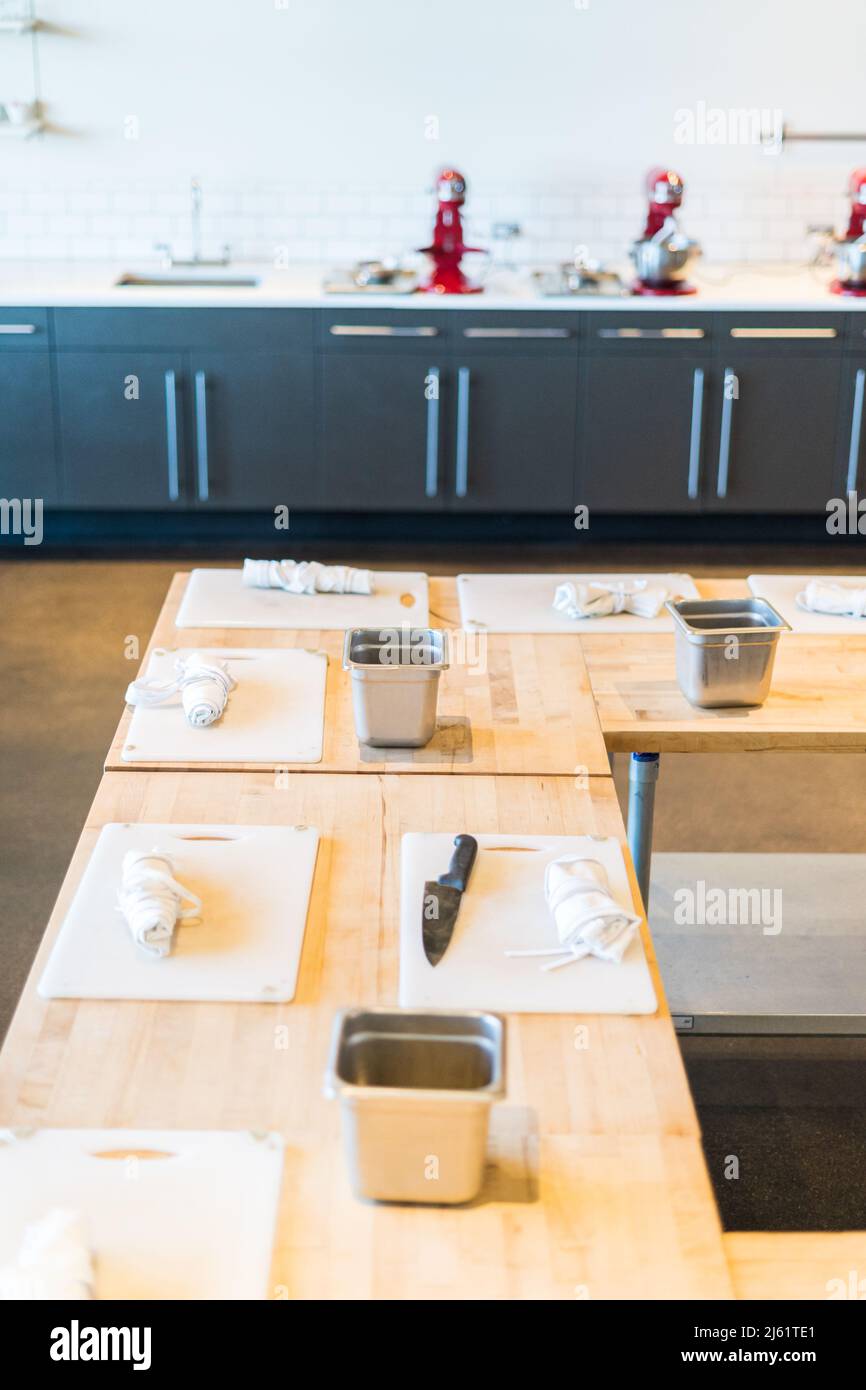 Tables prepared with white cutting boards and aprons for cooking class ...