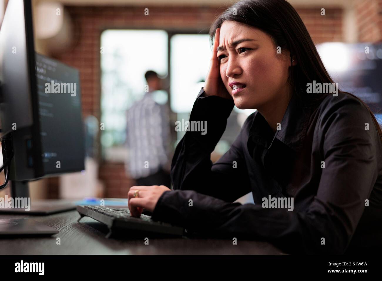 Confused tech engineer sitting doubtful at computer trying to solve ...