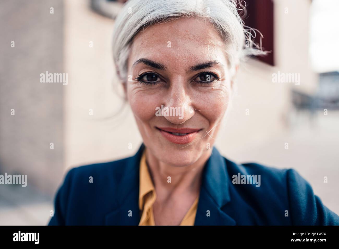 Smiling businesswoman with gray hair outside office building Stock ...