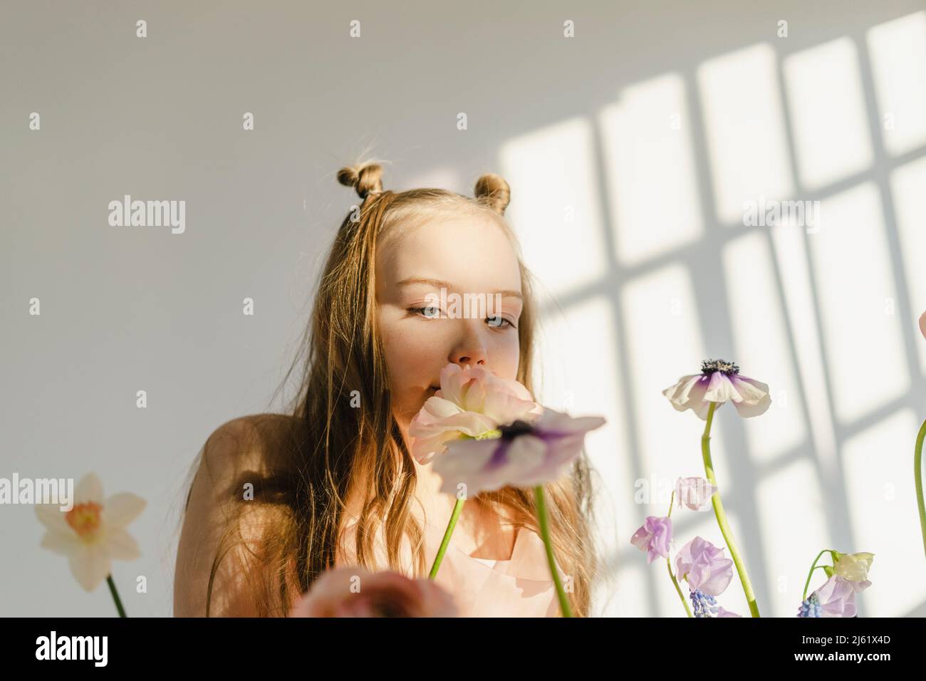 Girl smelling fresh flowers in front of white wall Stock Photo - Alamy