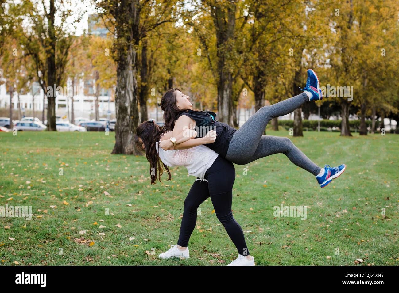 Woman piggybacking her sister in public park Stock Photo - Alamy