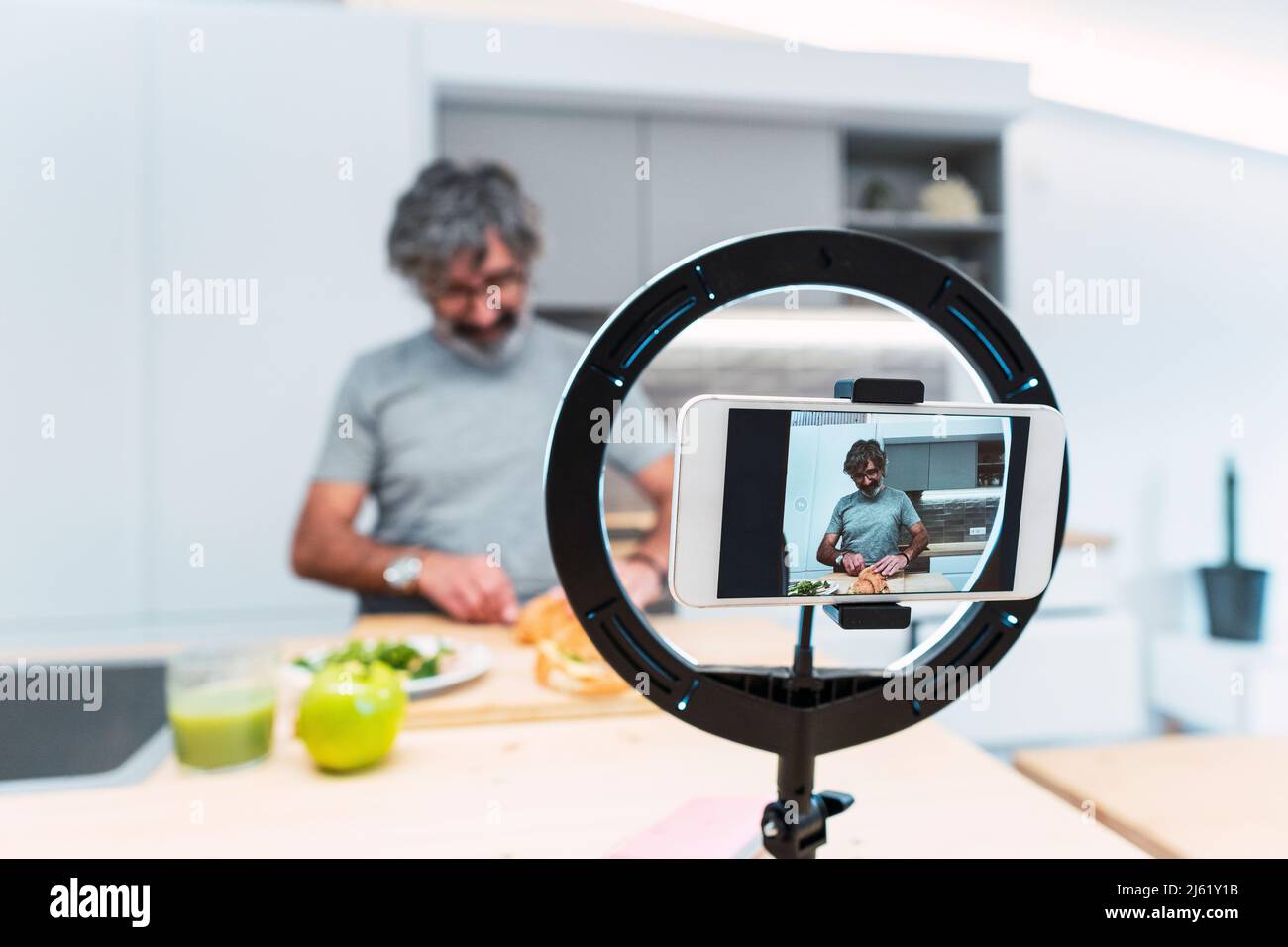 Senior man cooking and vlogging through mobile phone at home Stock ...