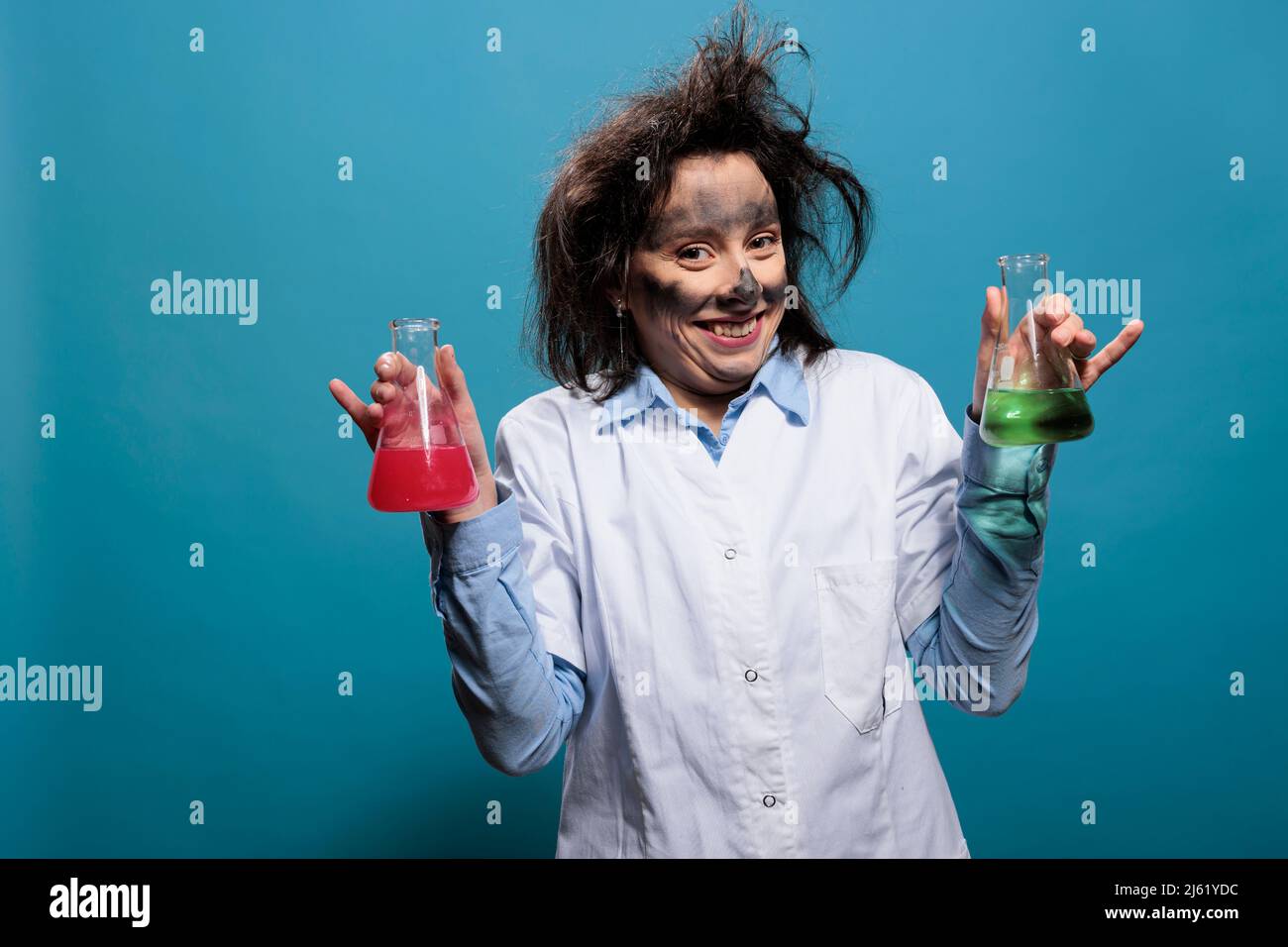 Silly looking mad chemistry expert with messy hair holding glass flasks ...