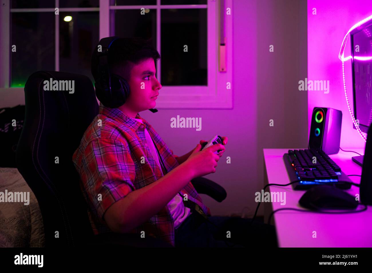 Boy with game controller sitting on chair in bedroom at home Stock ...