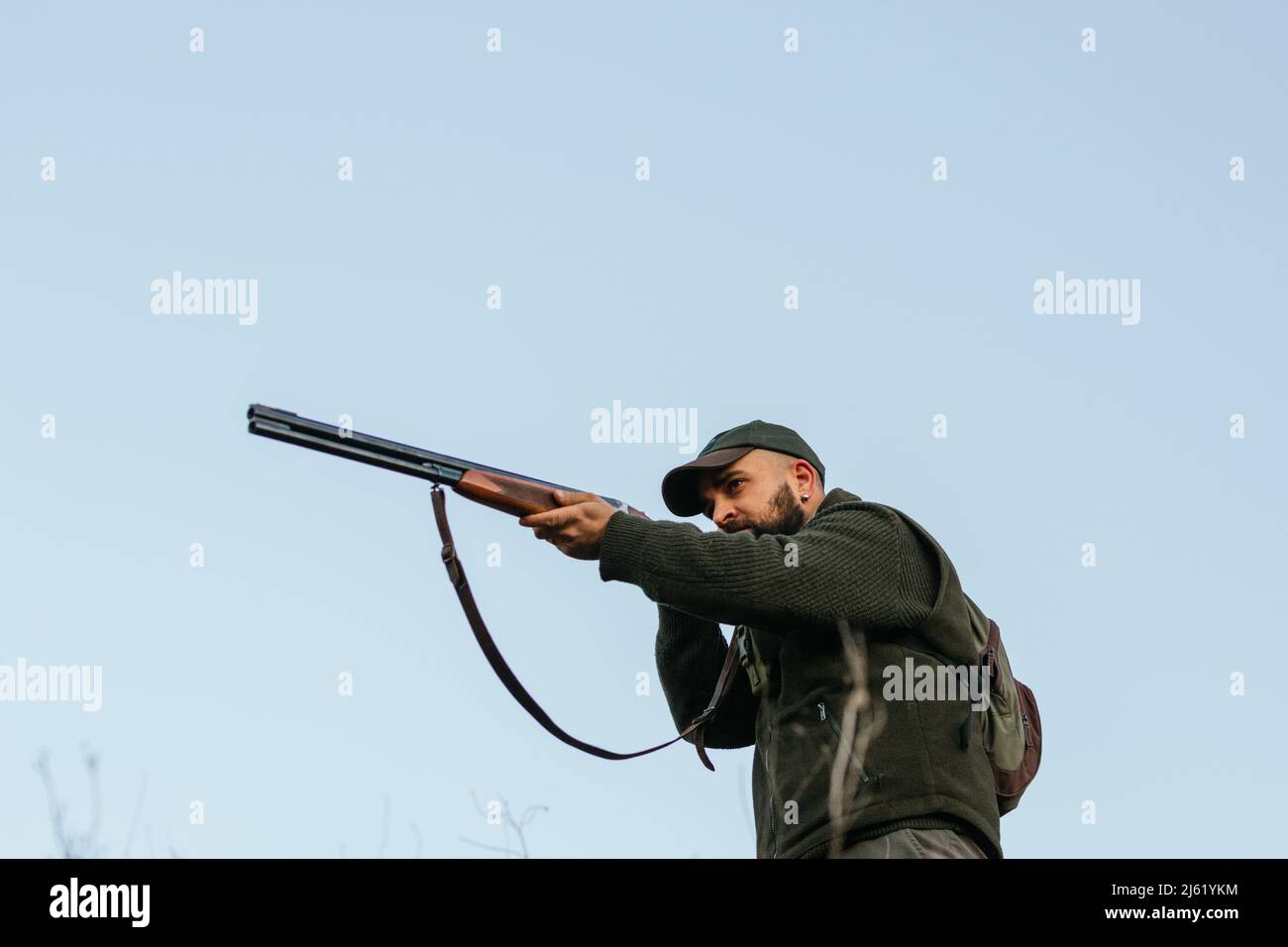 Hunter aiming with his gun with sky in background Stock Photo - Alamy