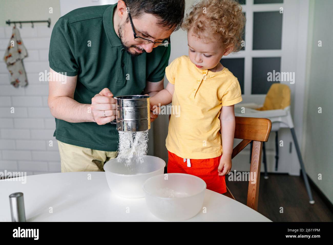 Man with daughter sieving flour at table in kitchen Stock Photo - Alamy