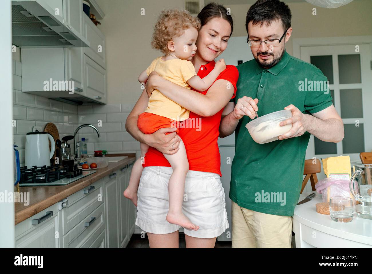 Man holding bowl standing by woman carrying daughter in kitchen Stock ...