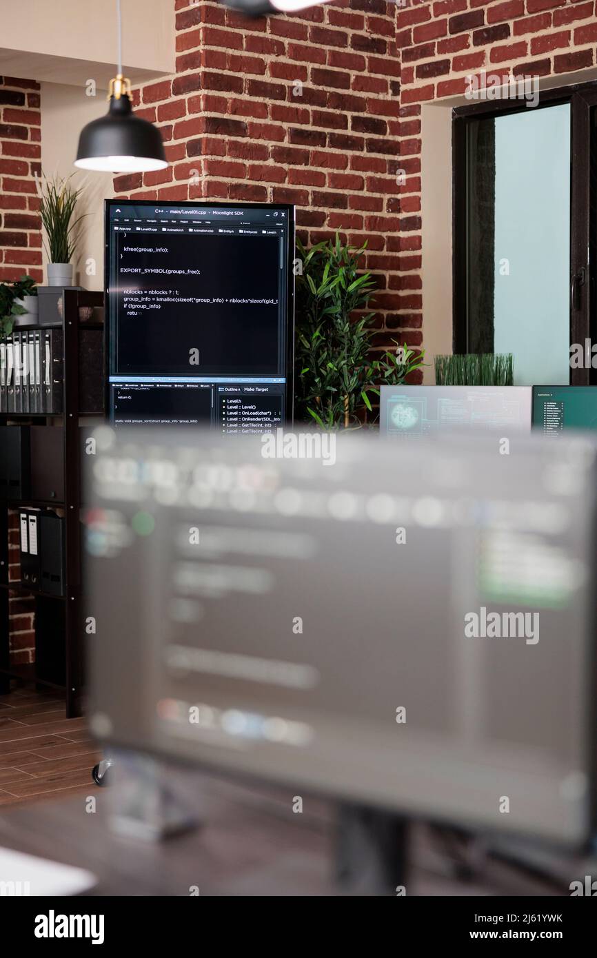Interior of empty data center office with multiple computer screens showing programming line ...