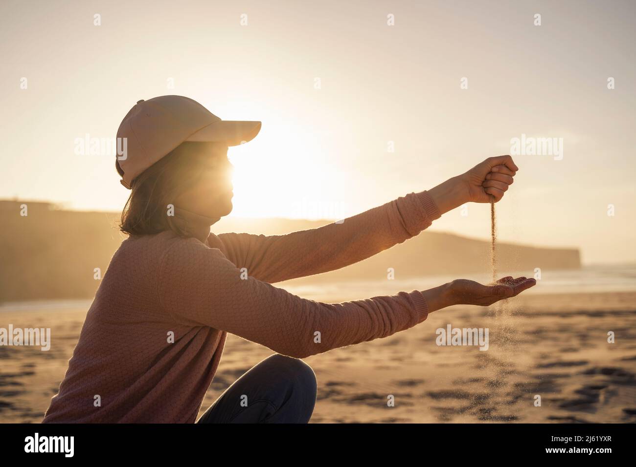 Sand falling out of woman's closed fist at sunset Stock Photo - Alamy
