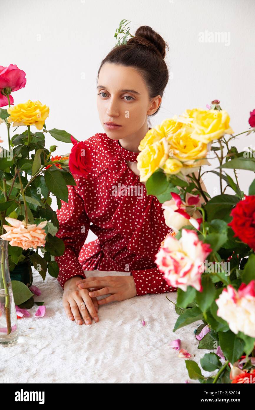 Beautiful young woman with colorful roses against white background ...