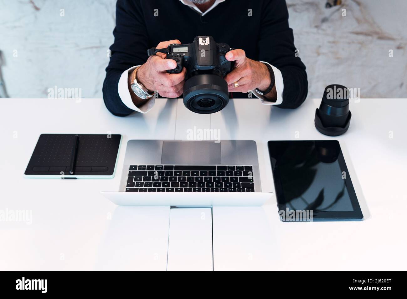 Freelancer holding camera sitting with wireless technologies at table ...