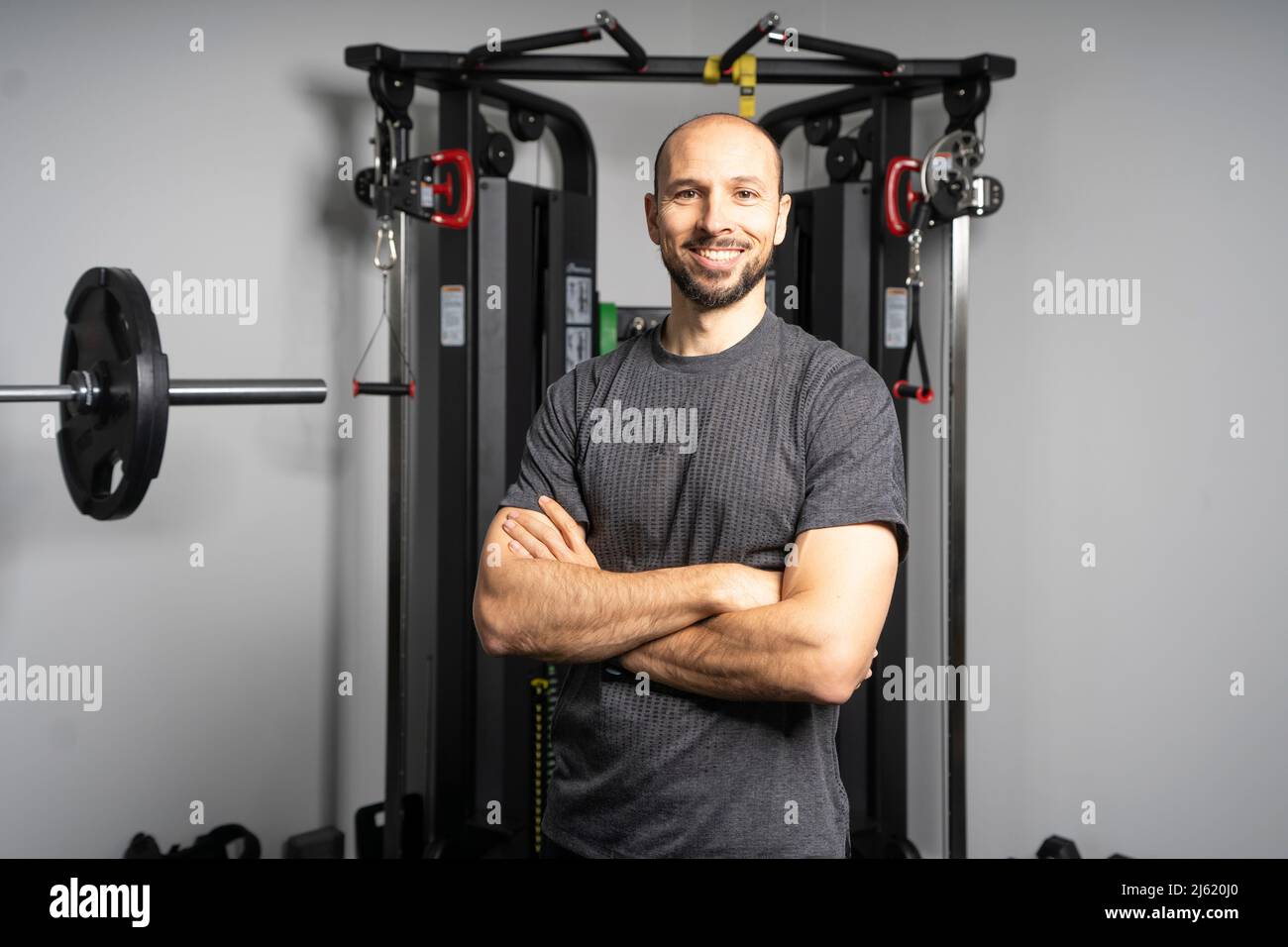 Smiling fitness instructor standing with arms crossed in front of ...